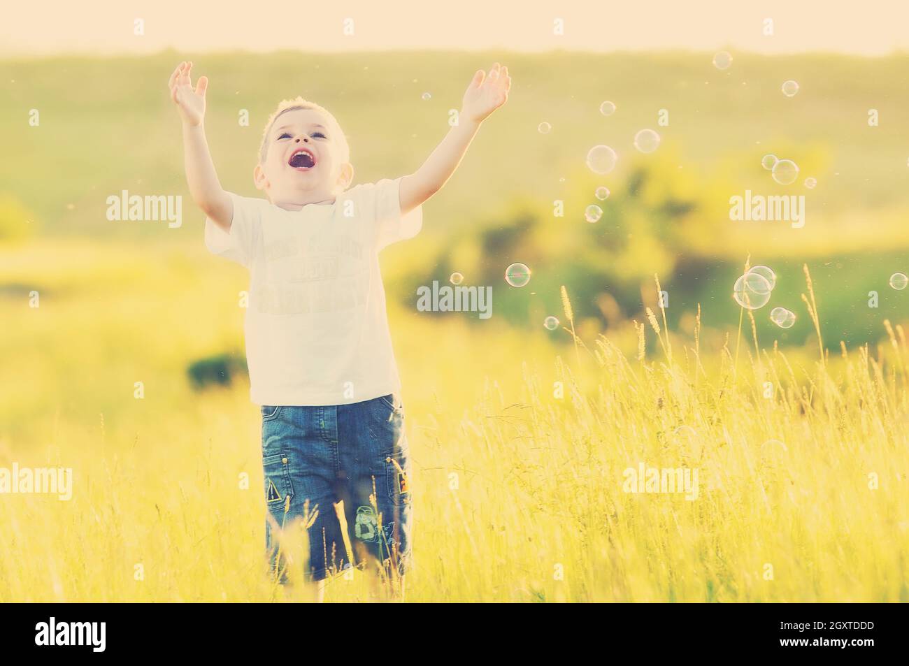 happy young beautiful child have fun on eadow with soap bubbles toy ...