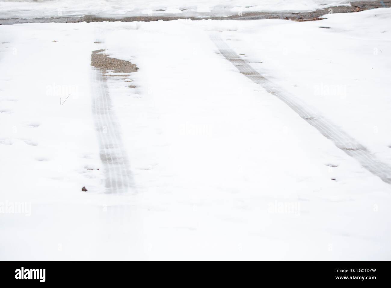 Tire tracks on a dangerously slick driveway covered in winter ...