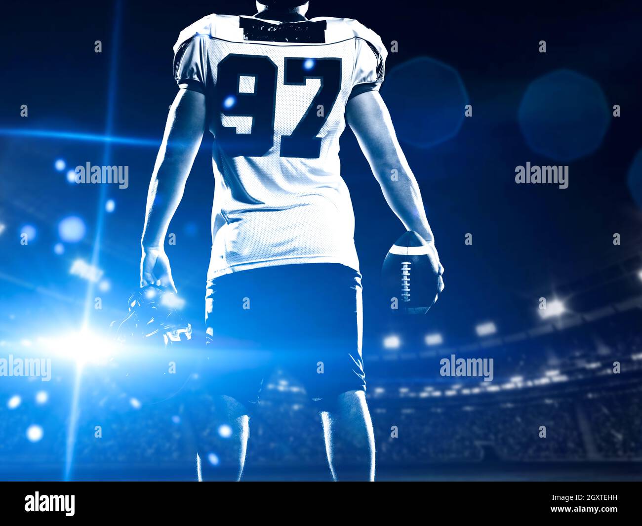 rear view of young confident American football player on field at night ...