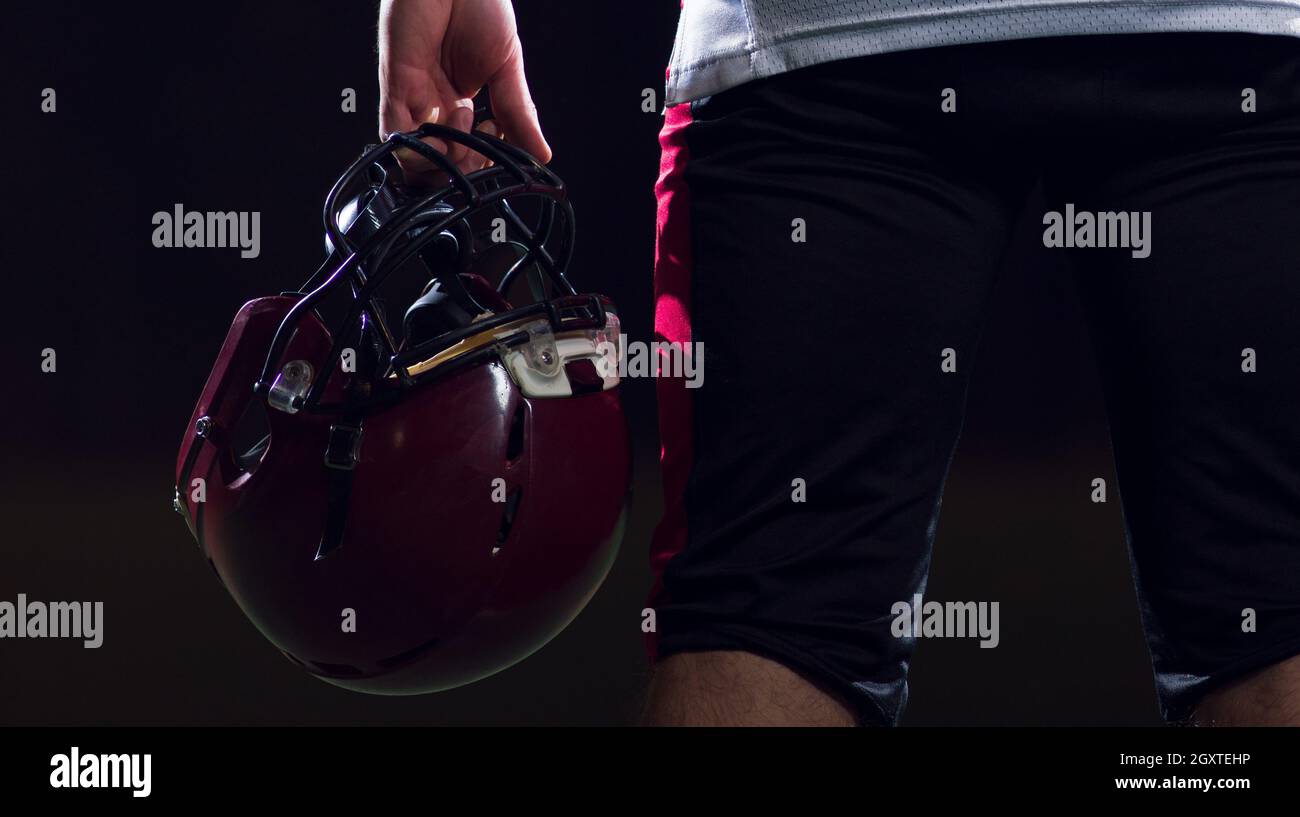 rear view of young confident American football player on field at night ...