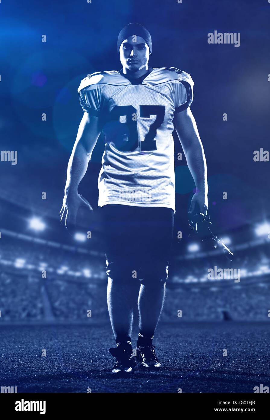 portrait of young confident American football player on field at night ...