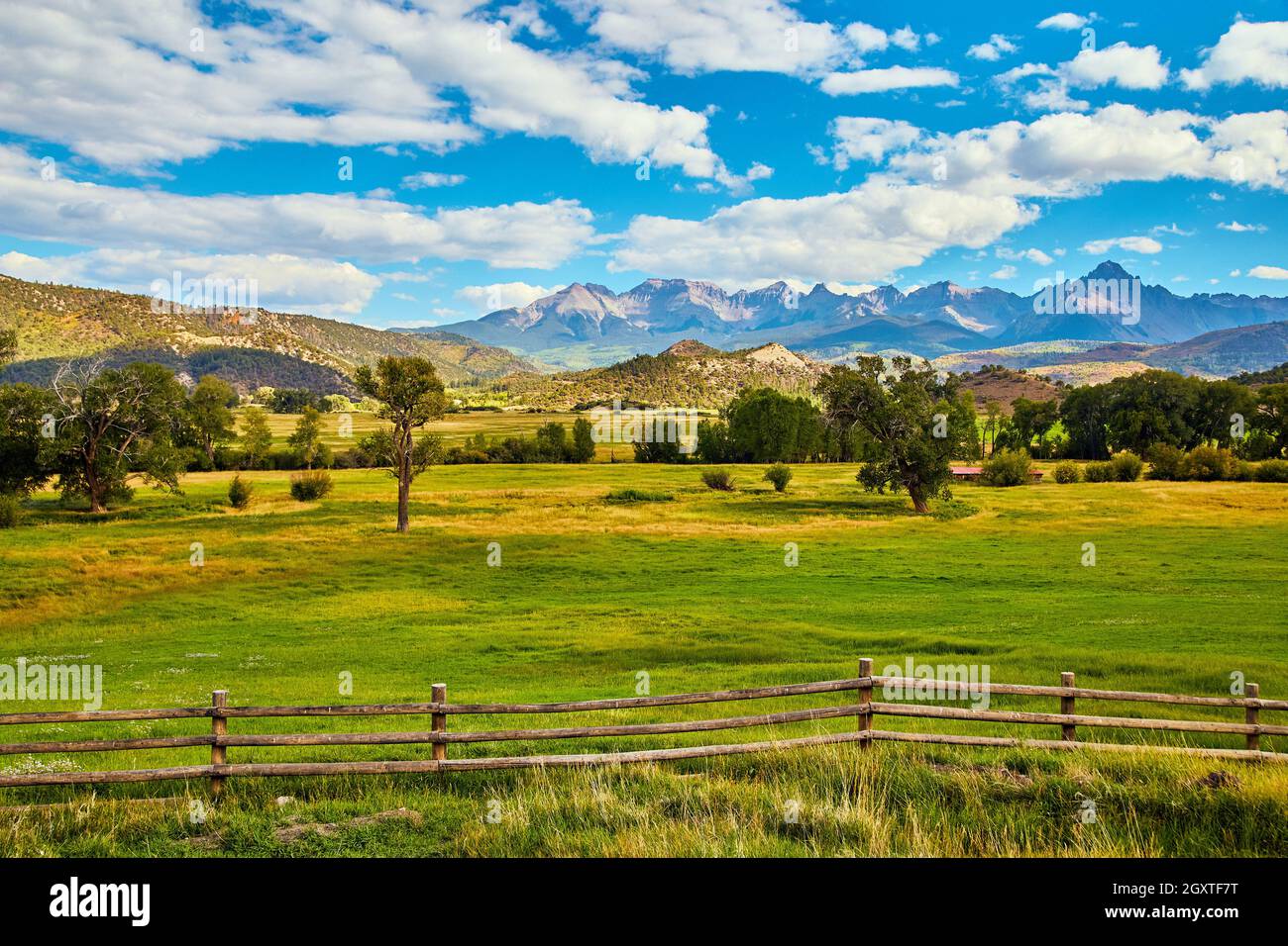 Open field with wood fence and lone tree with beautiful mountain range ...