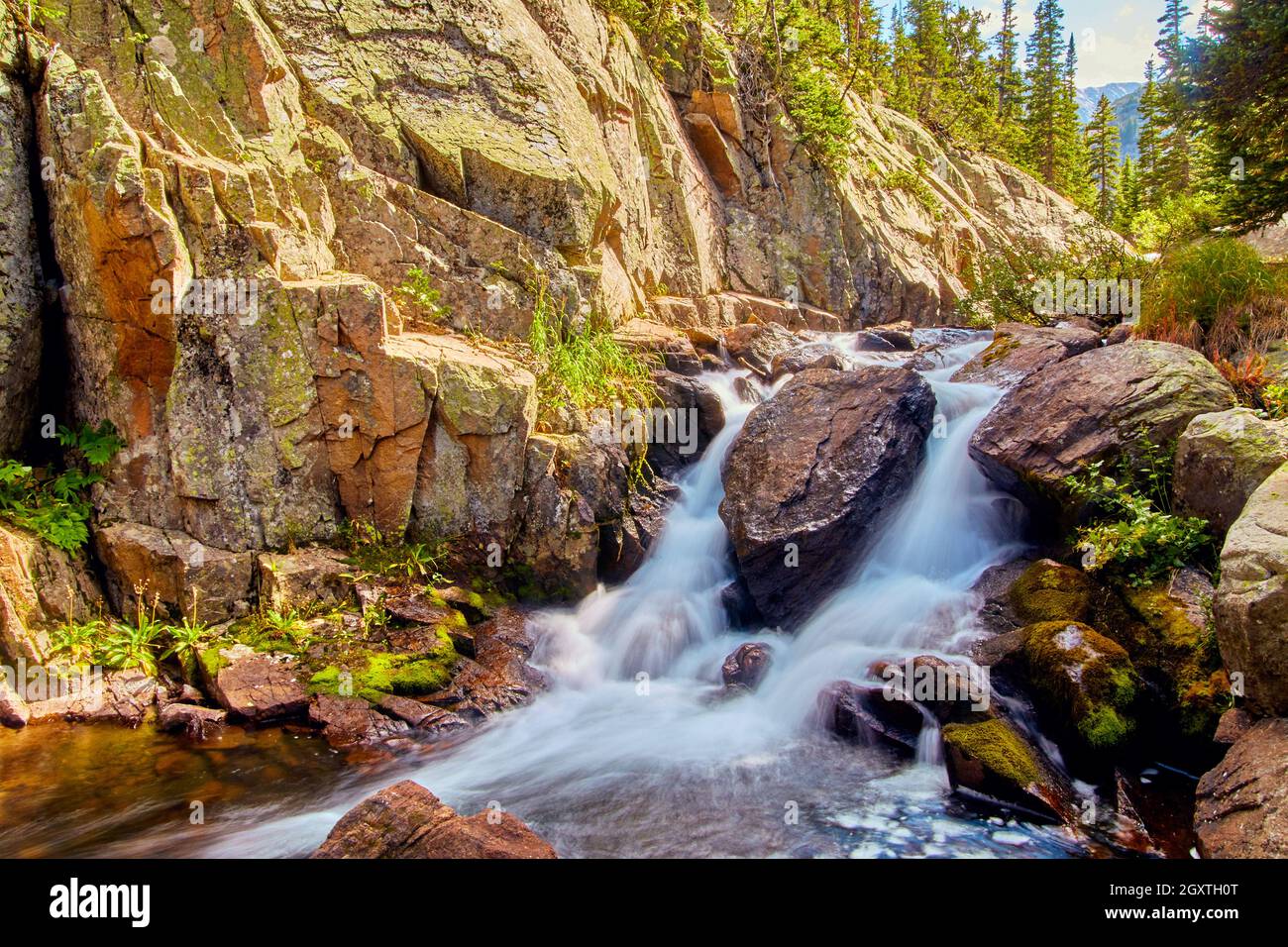 Waterfall through large boulders in mountains with lichen rocks Stock ...