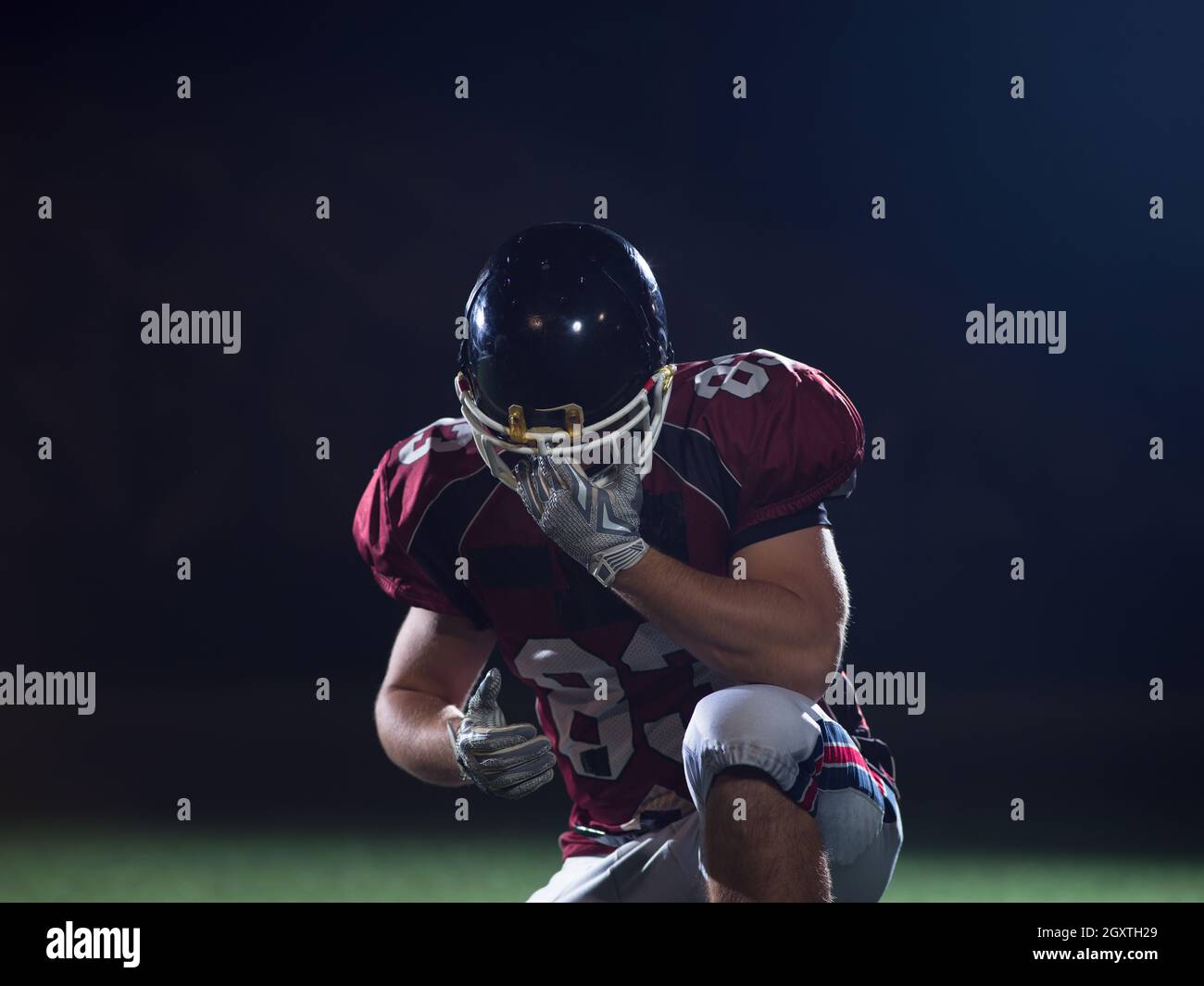 portrait of young confident American football player on field at night ...