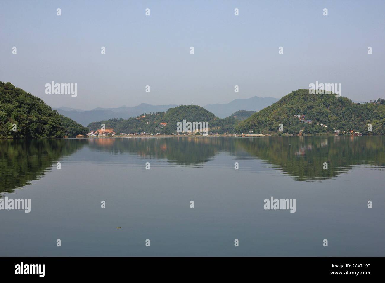Morning scene at Begnas lake, Nepal. Hills covered by forest mirroring ...