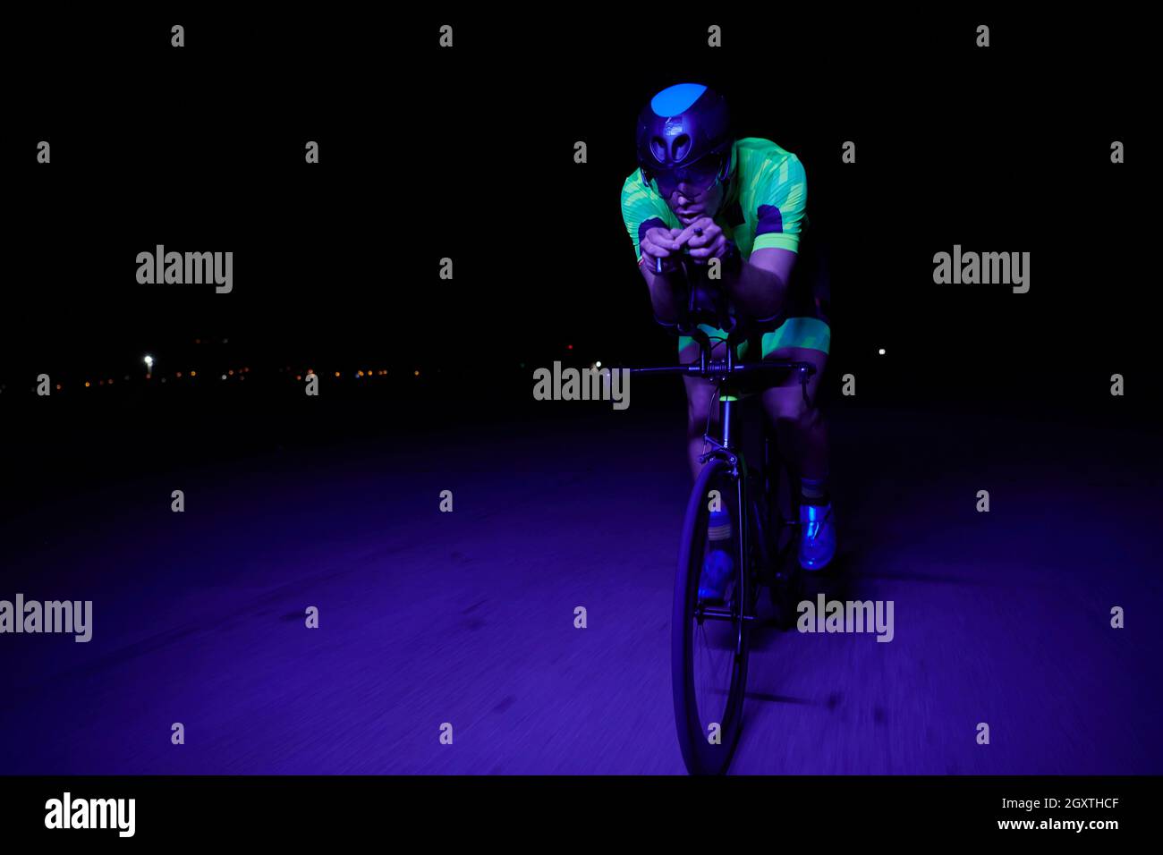 triathlon athlete cycling fast riding professional racing bike at night ...
