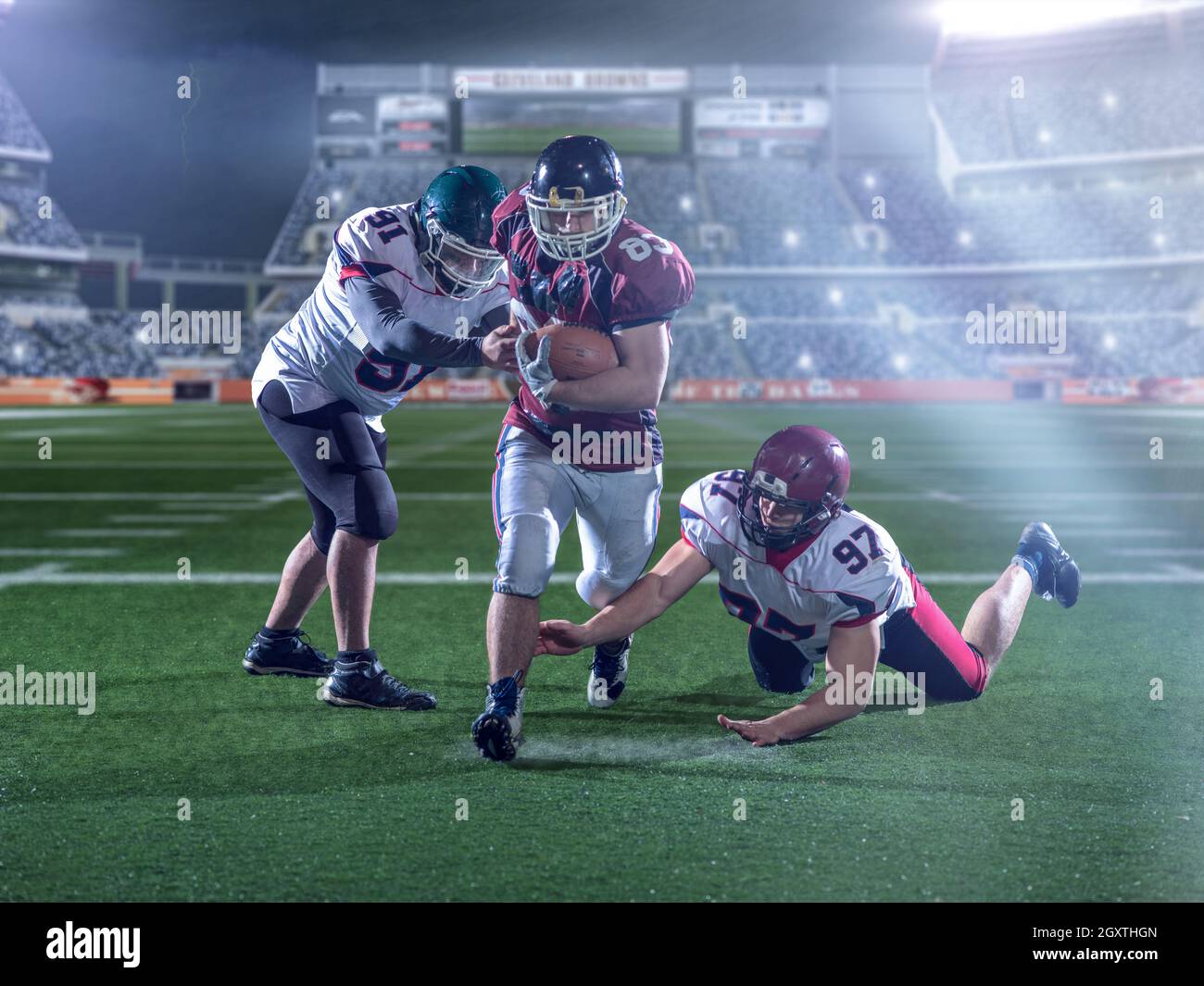 Front view of American football players in action at night game time on ...