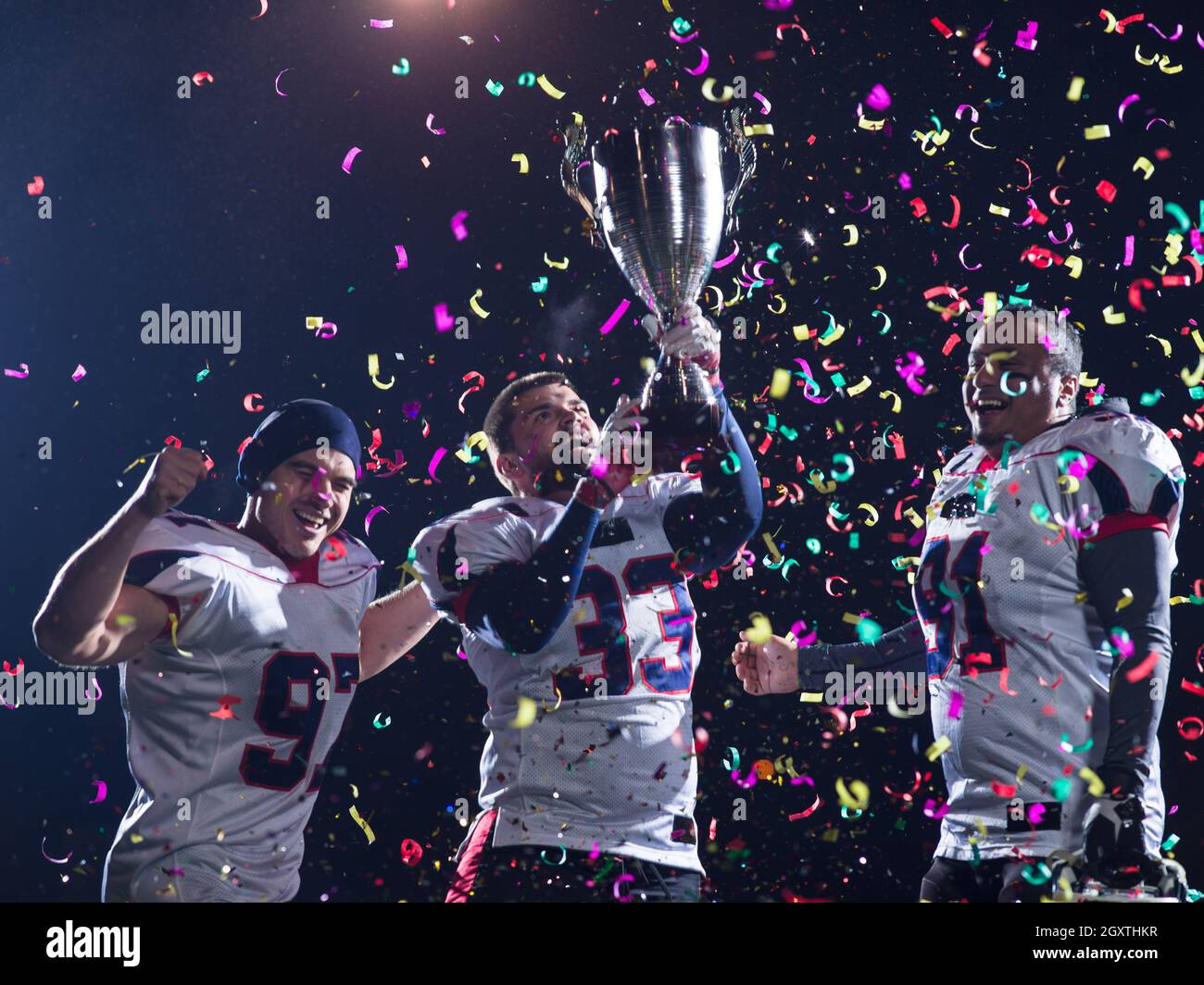 happy american football team celebrating victory with trophy and ...
