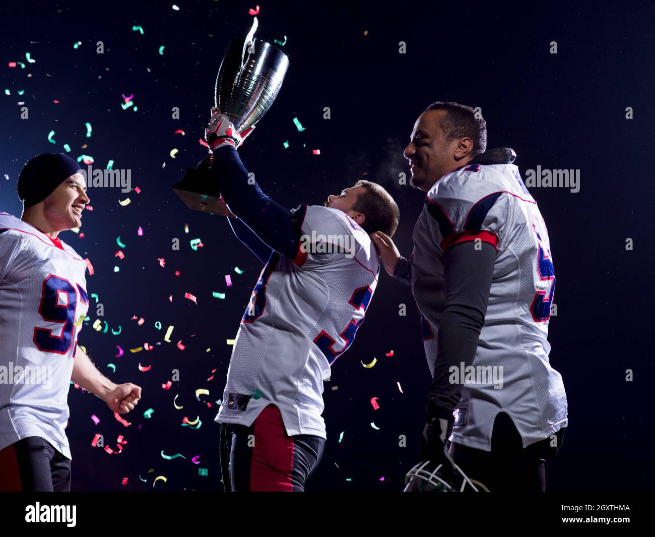 happy american football team celebrating victory with trophy and ...