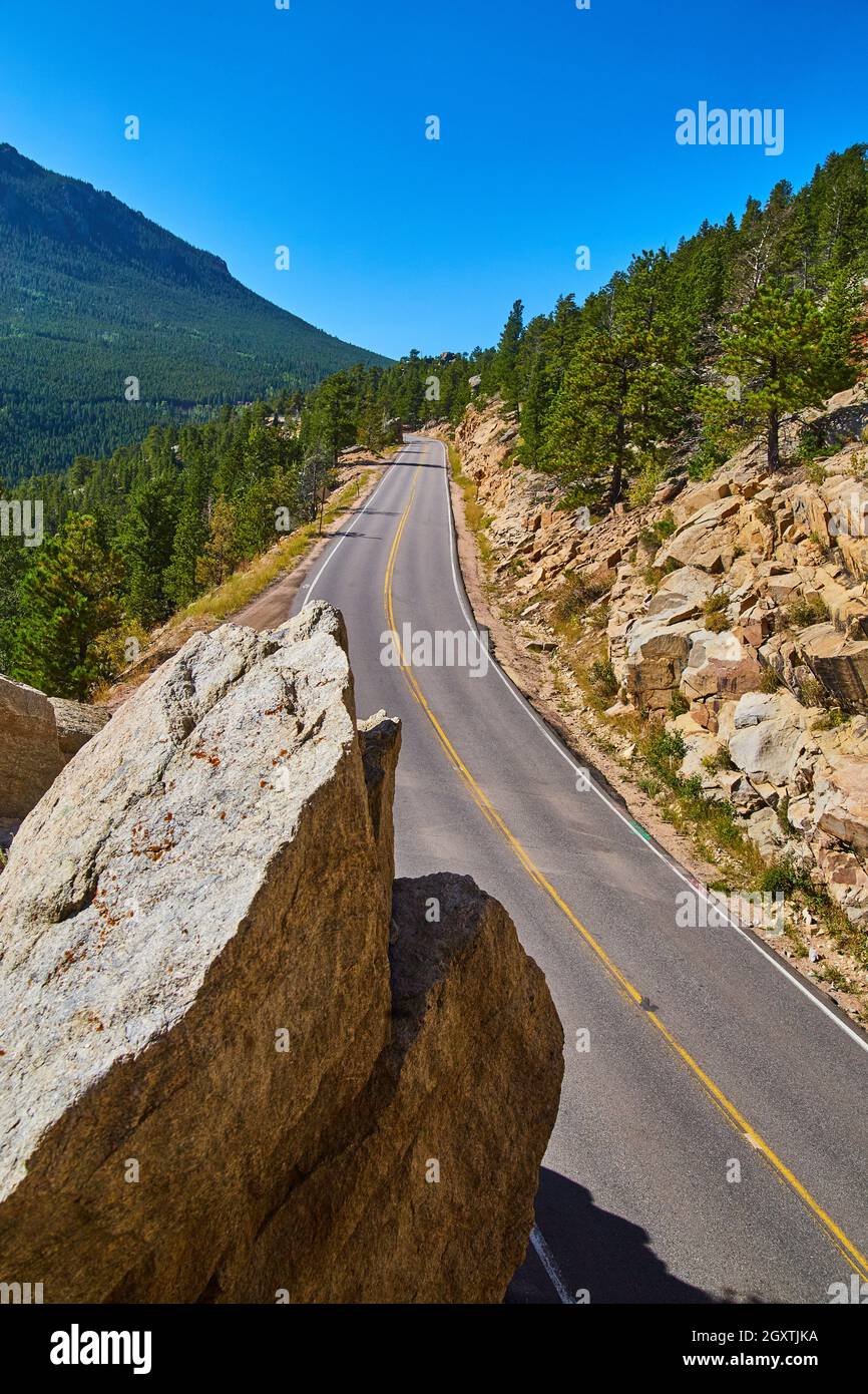 Vertical road cutting through mountains next to large boulders Stock ...