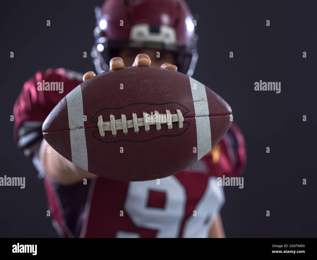Portrait of american football player showing football to camera against ...