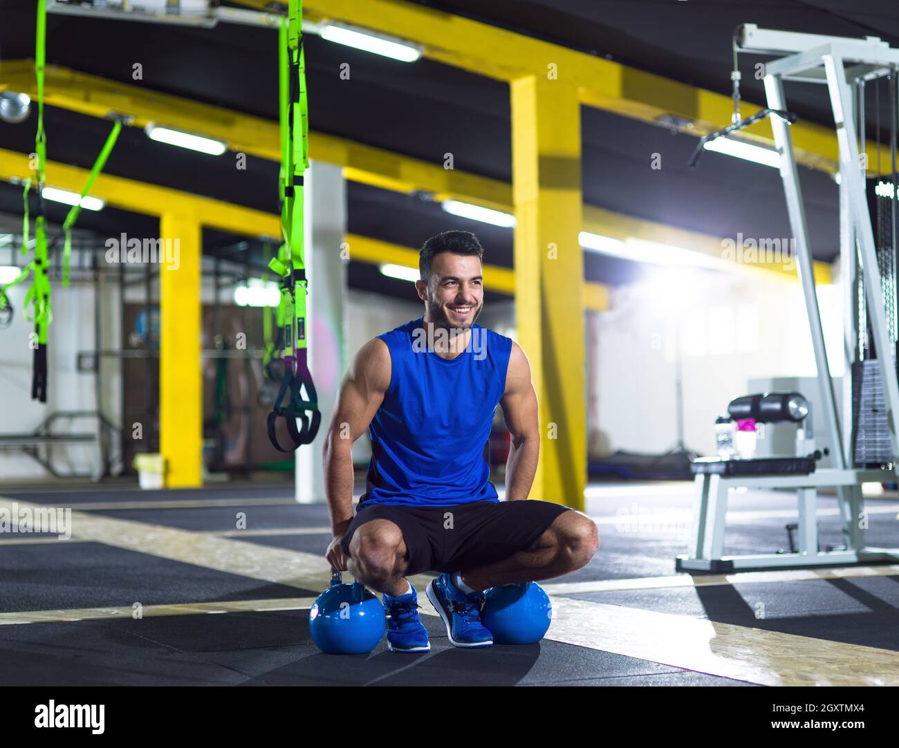Young strong man doing pushups on kettlebells at cross fitness gym ...