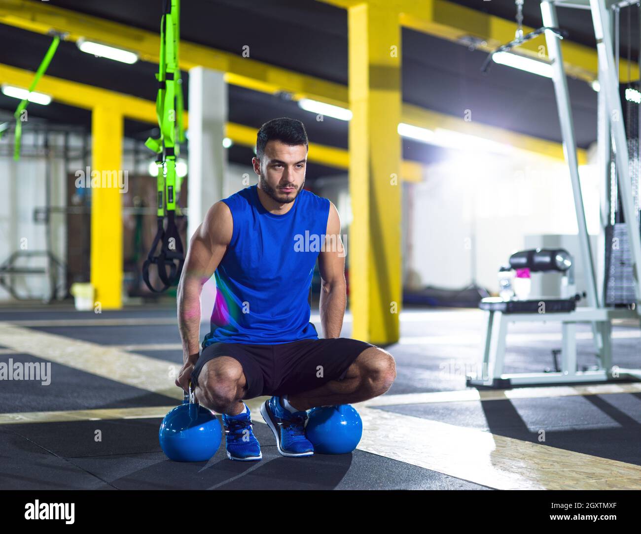 Young strong man doing pushups on kettlebells at cross fitness gym ...