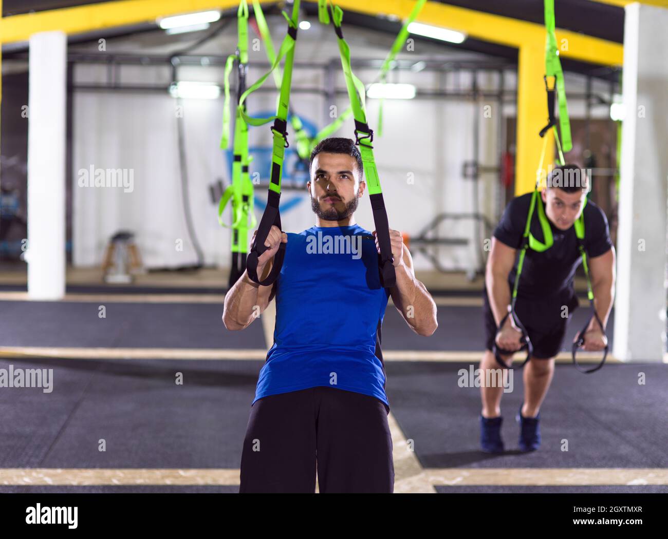 two young athlete men working out pull ups with gymnastic rings at the ...