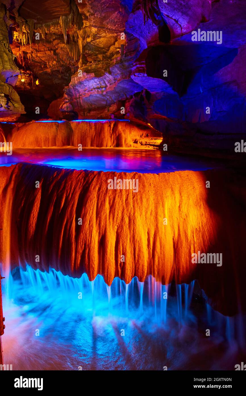 Waterfalls in underground cave flowing over rock formations with orange ...
