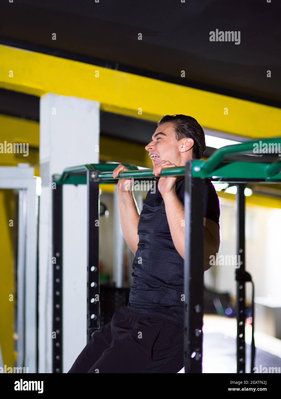 young muscular man doing pull ups on the horizontal bar as part of ...