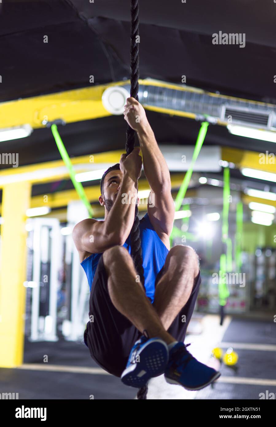 young muscular man doing rope climbing in fitness gym Stock Photo - Alamy