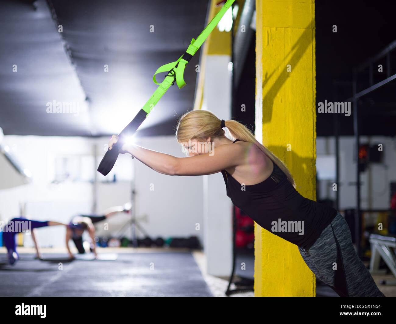young athlete woman working out pull ups with gymnastic rings at the ...