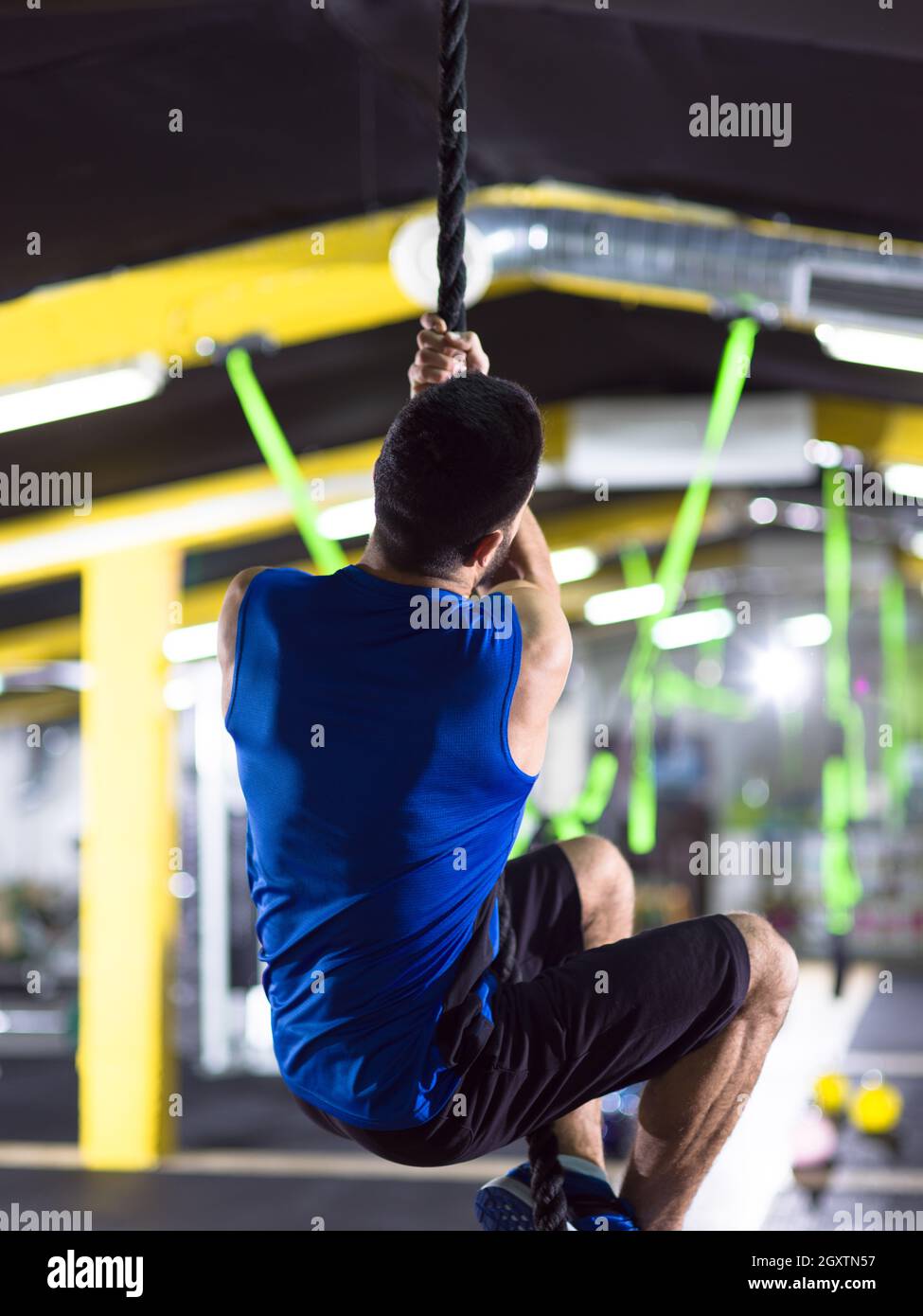 young muscular man doing rope climbing in crossfitness gym Stock Photo ...