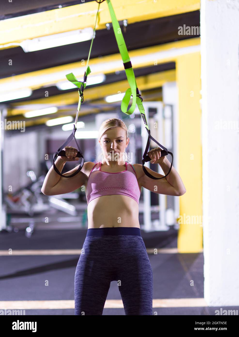 young athlete woman working out pull ups with gymnastic rings at the ...