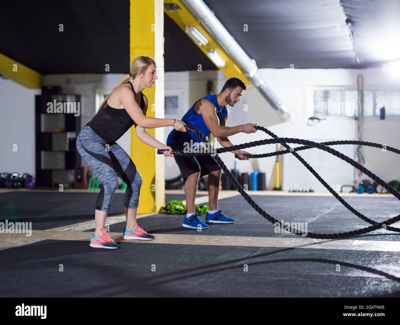 young fit sports couple working out in functional training gym doing ...