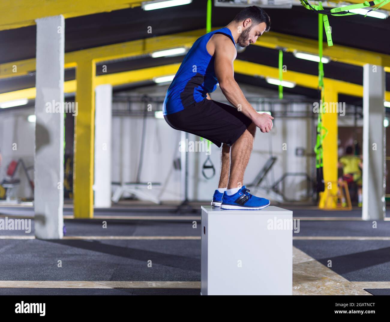 young athletic man training jumping on fit box at crossfitness gym ...