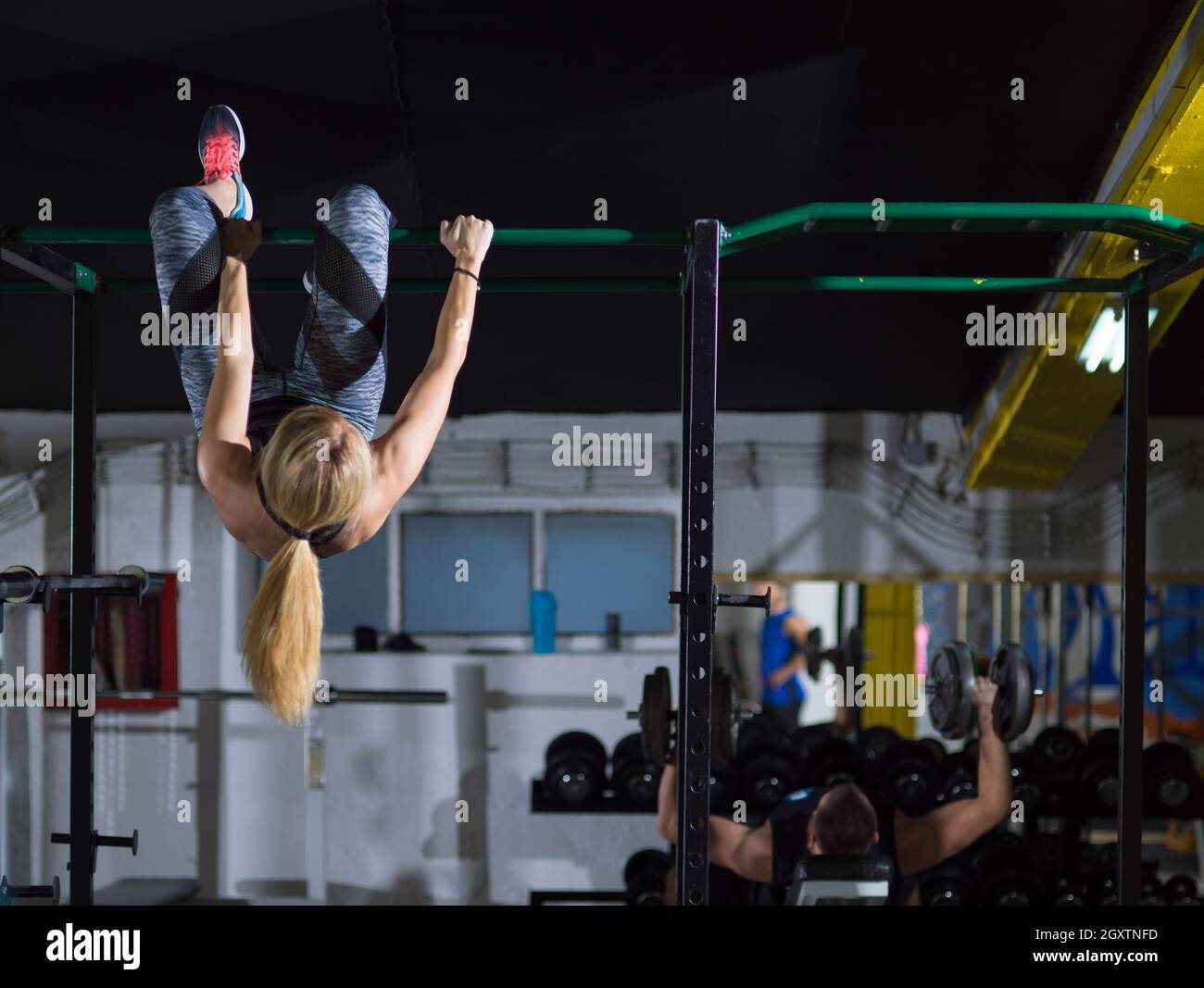 athlete woman doing abs exercises hanging upside down on horizontal bar ...