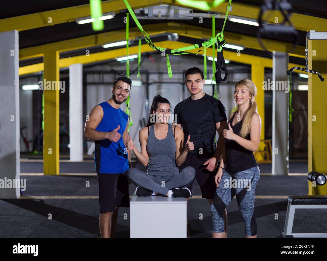 portrait of young healthy athletic people training jumping on fit box ...