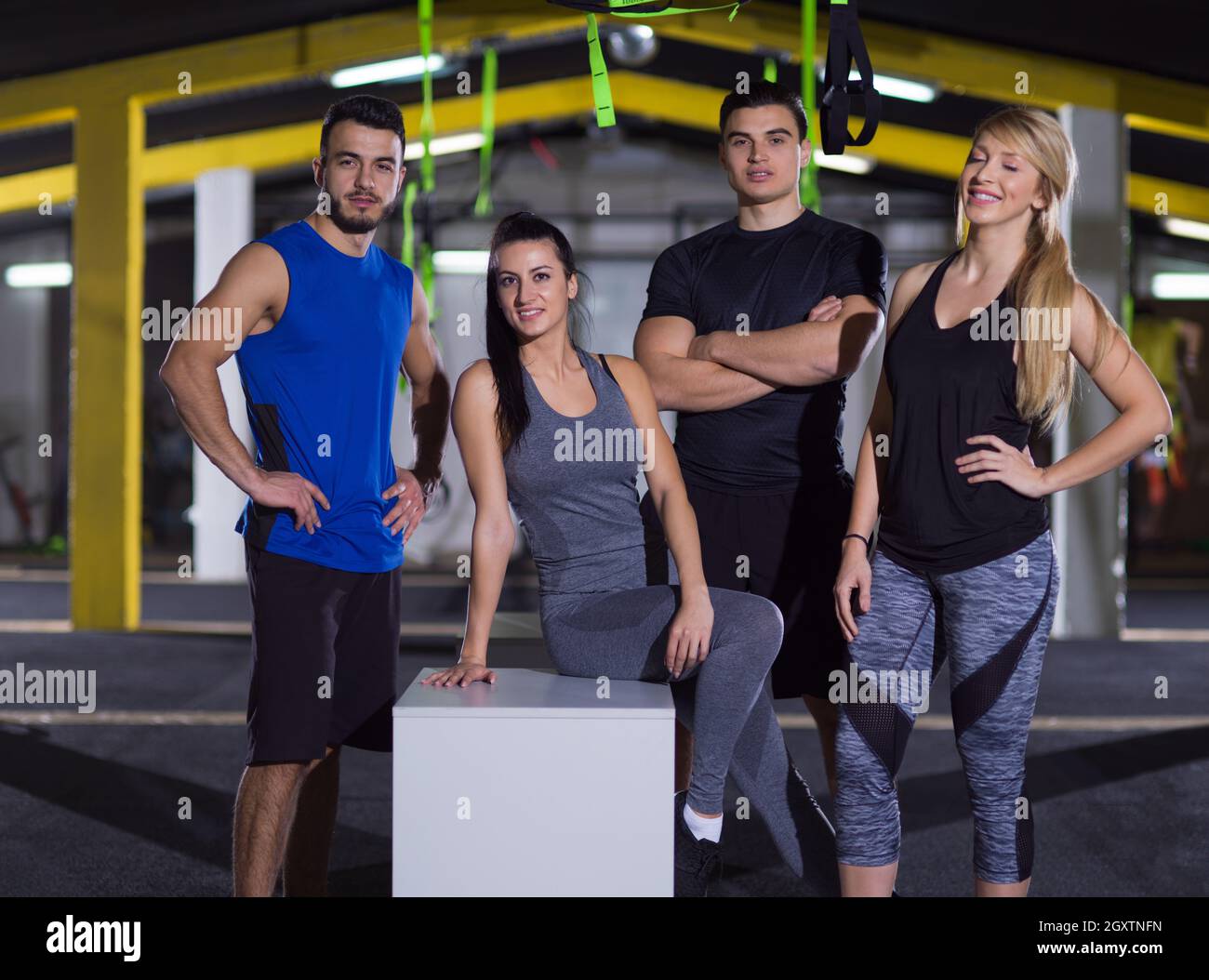 portrait of young healthy athletic people training jumping on fit box ...