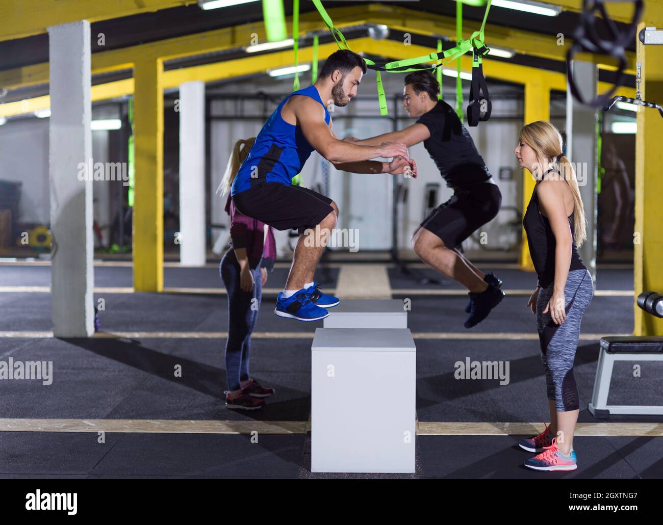 group of young healthy athletic people training jumping on fit box at ...