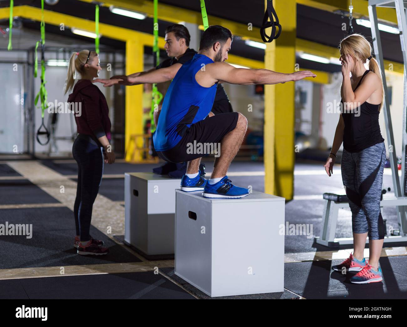 group of young healthy athletic people training jumping on fit box at ...