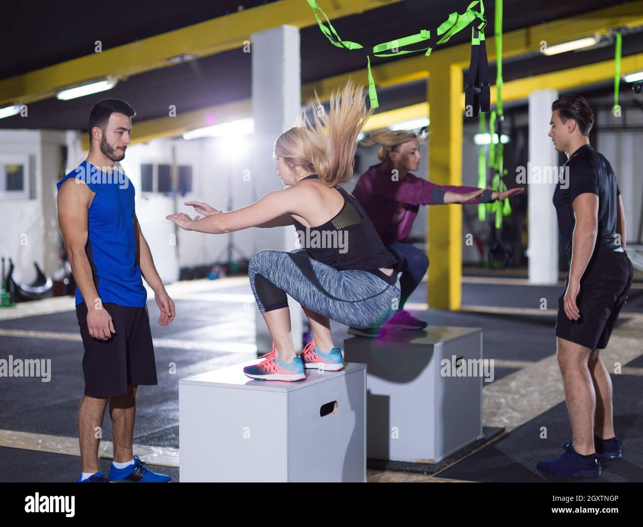 group of young healthy athletic people training jumping on fit box at ...