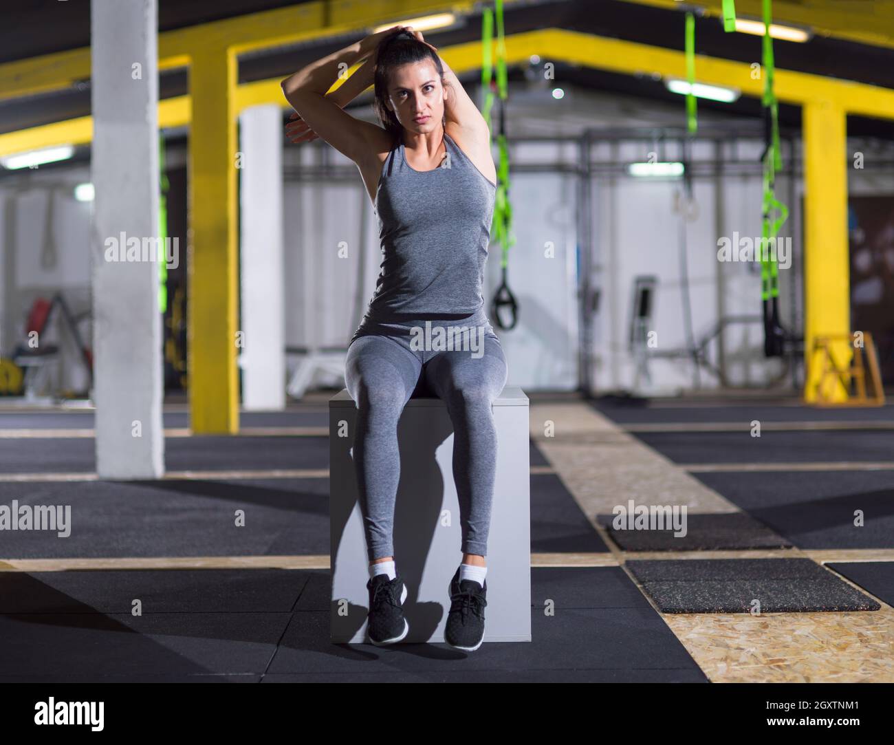 young athletic woman warming up and stretching on fit box at ...