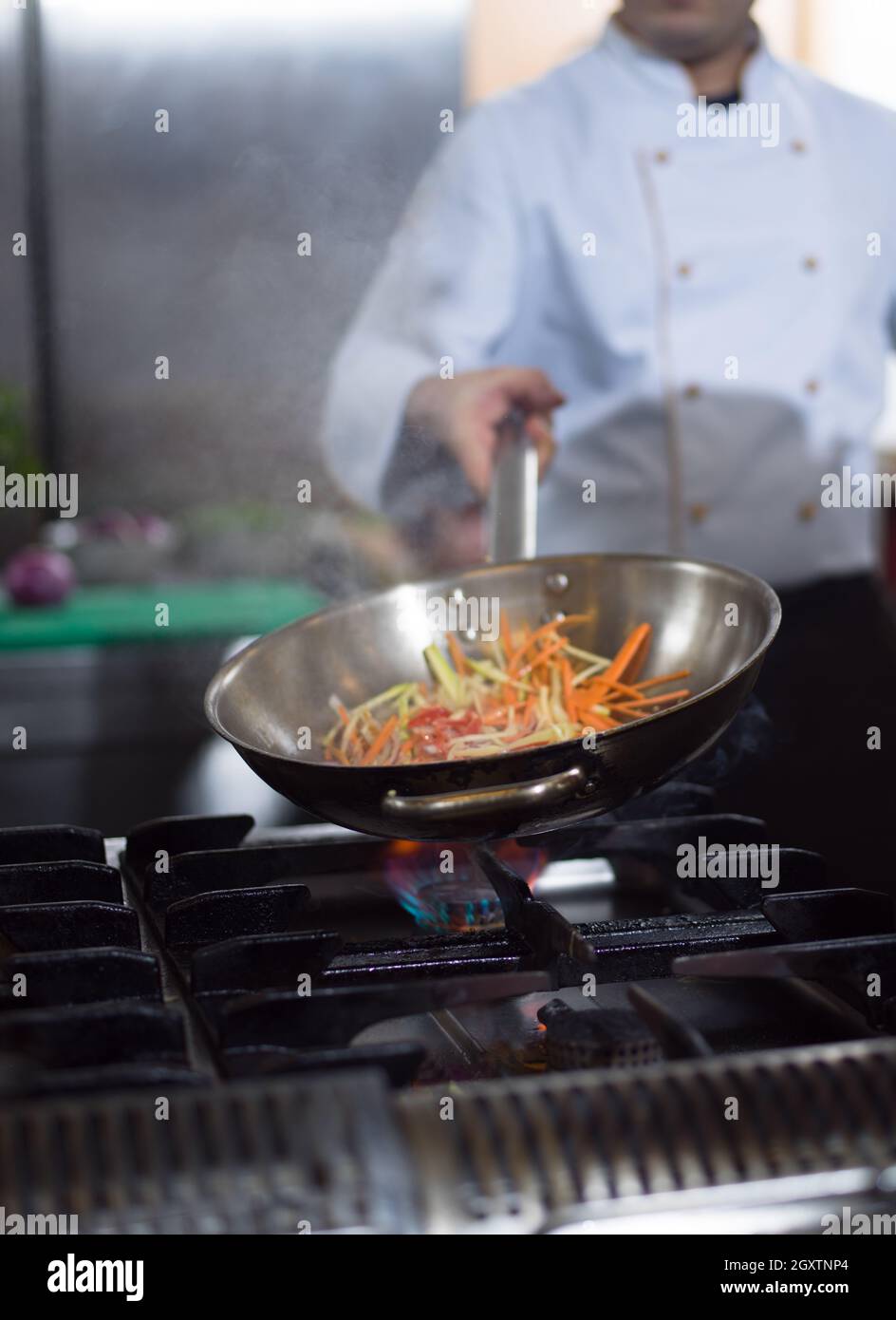 Chef cooking and doing flambe on food in restaurant kitchen Stock Photo ...
