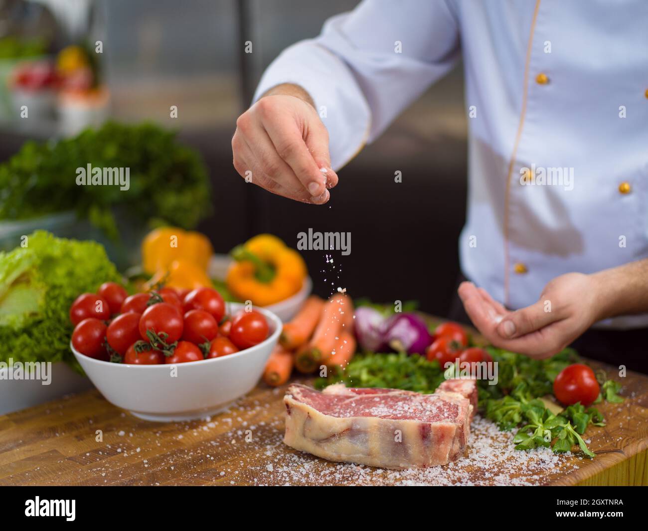 Master Chef hands putting salt on juicy slice of raw steak with ...