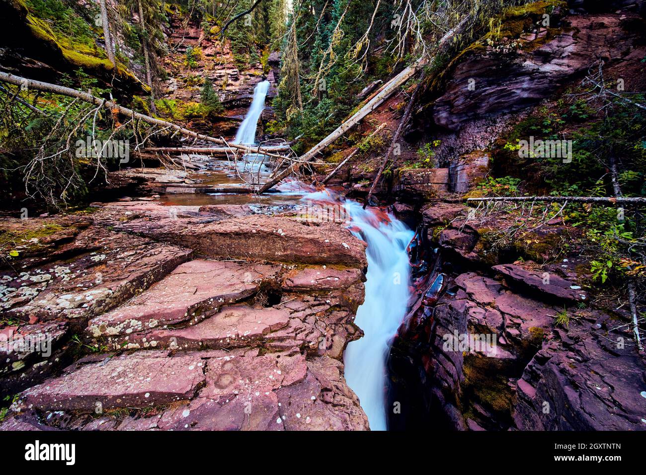 Water rushing through deep gorge with red rocks and waterfall in ...