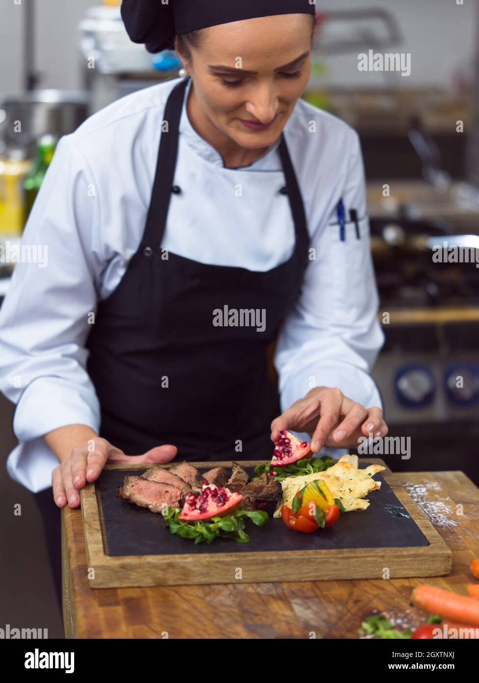 female Chef in hotel or restaurant kitchen preparing beef steak with ...