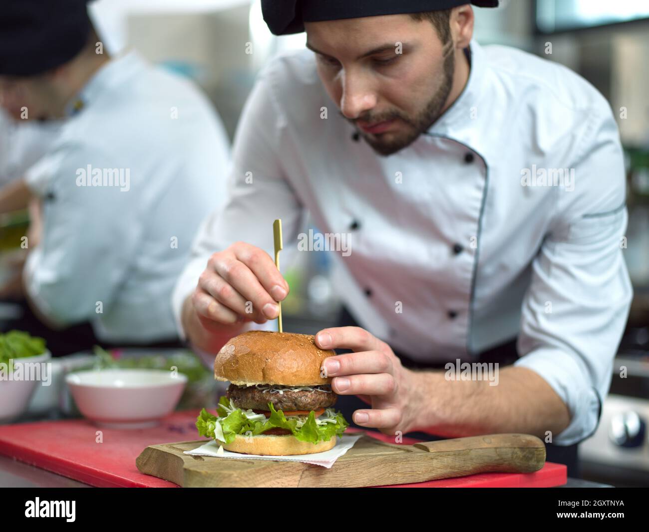 master chef putting toothpick on a burger in restaurant kitchen Stock ...