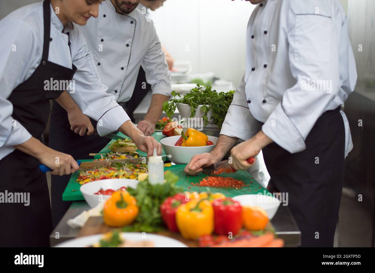 Professional team cooks and chefs preparing meals at busy hotel or ...