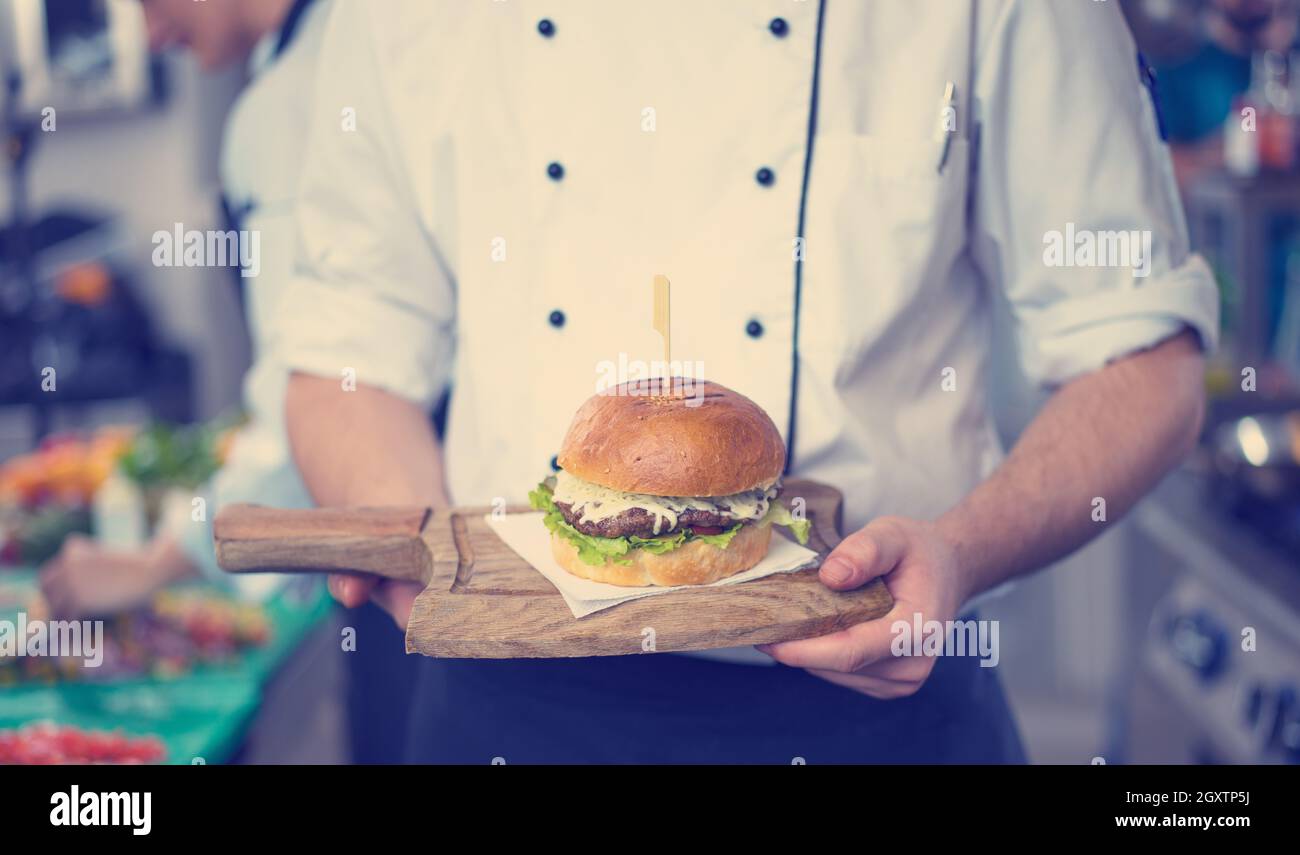 master chef putting toothpick on a burger in restaurant kitchen Stock ...
