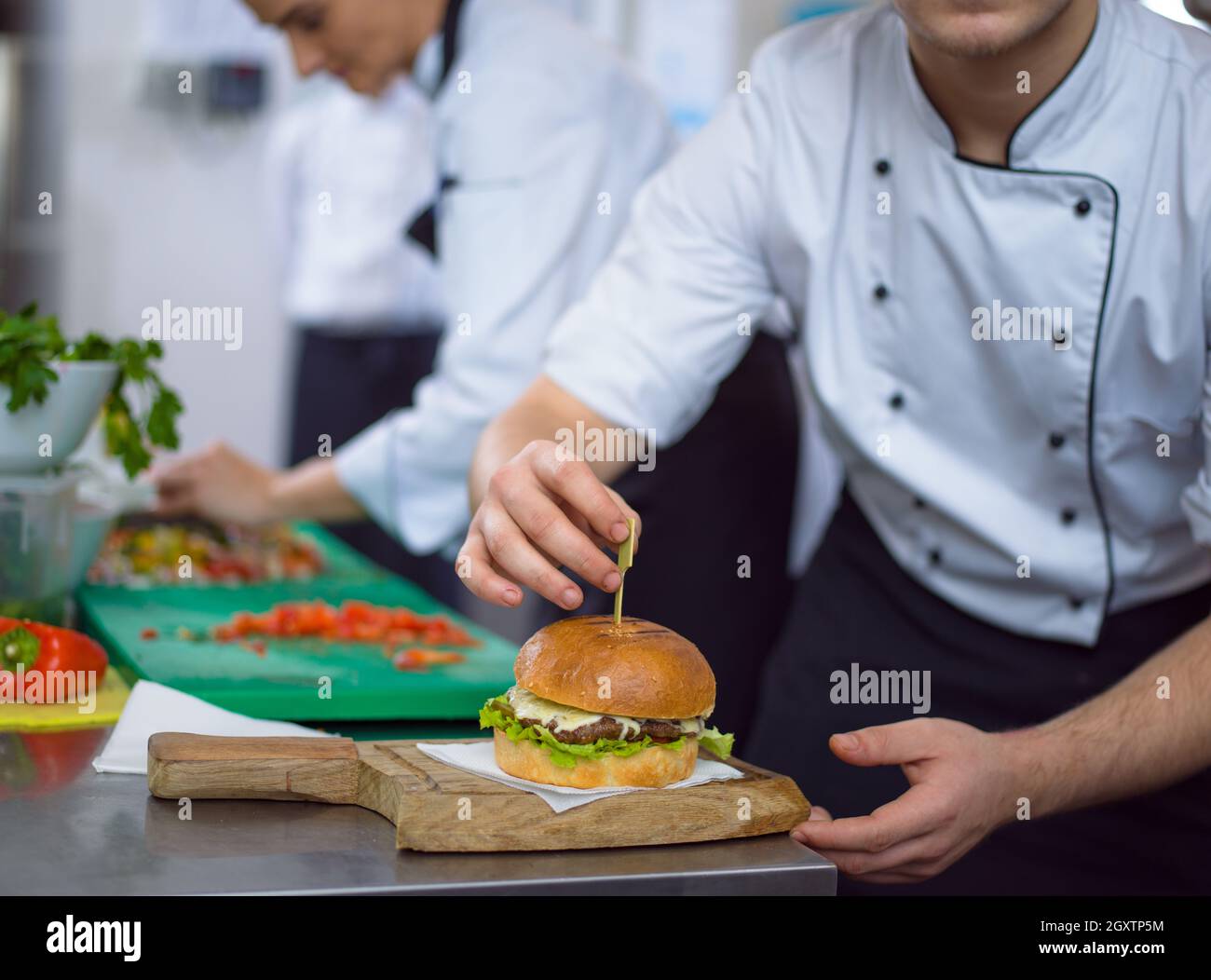 master chef putting toothpick on a burger in restaurant kitchen Stock ...