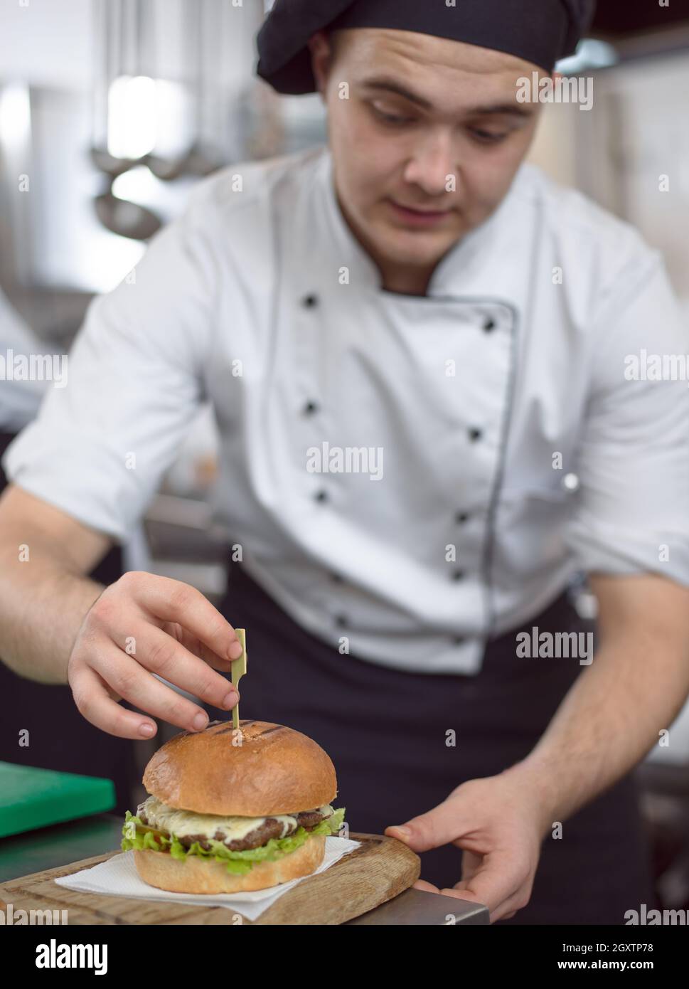 master chef putting toothpick on a burger in restaurant kitchen Stock ...