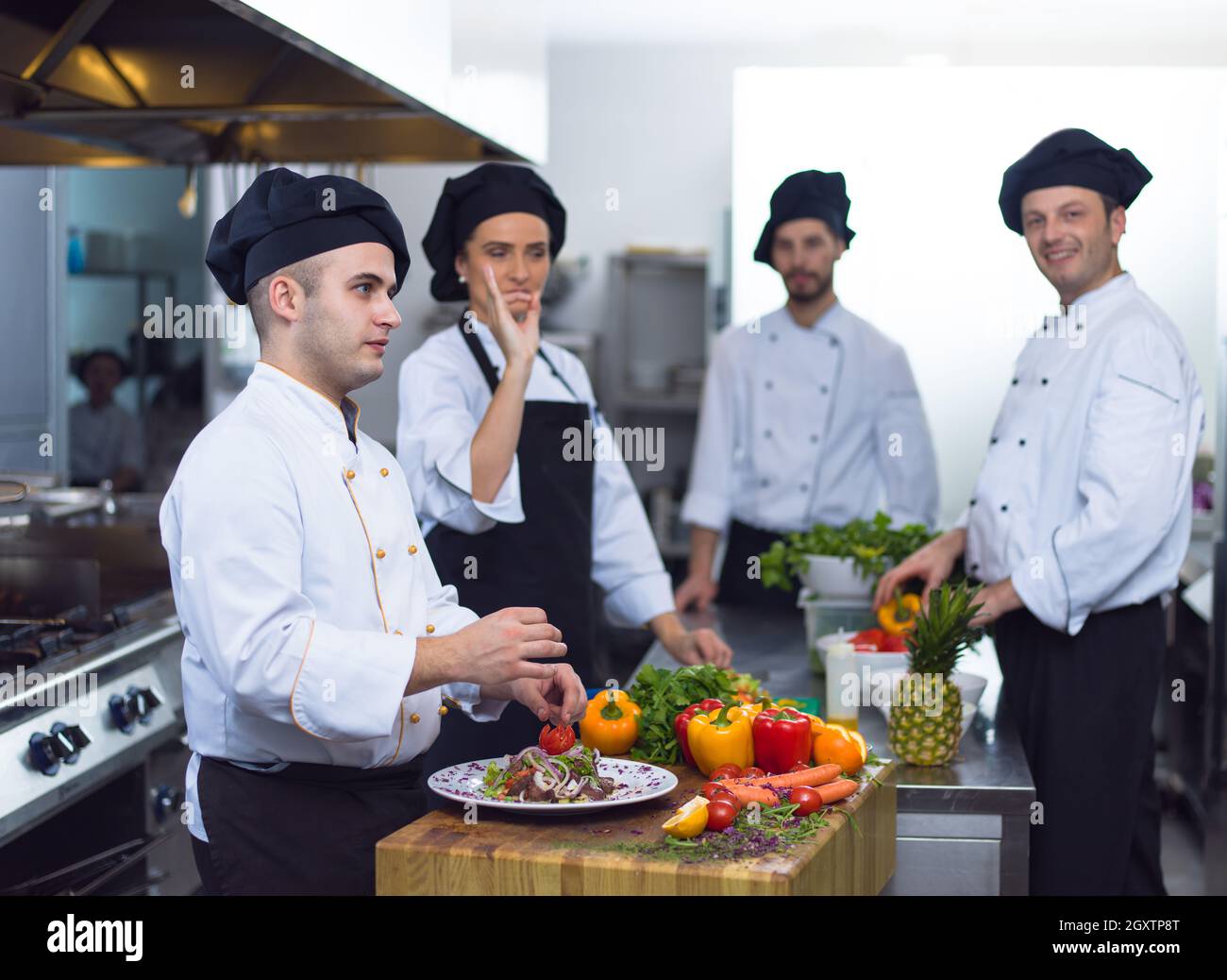 Professional team cooks and chefs preparing meals at busy hotel or ...