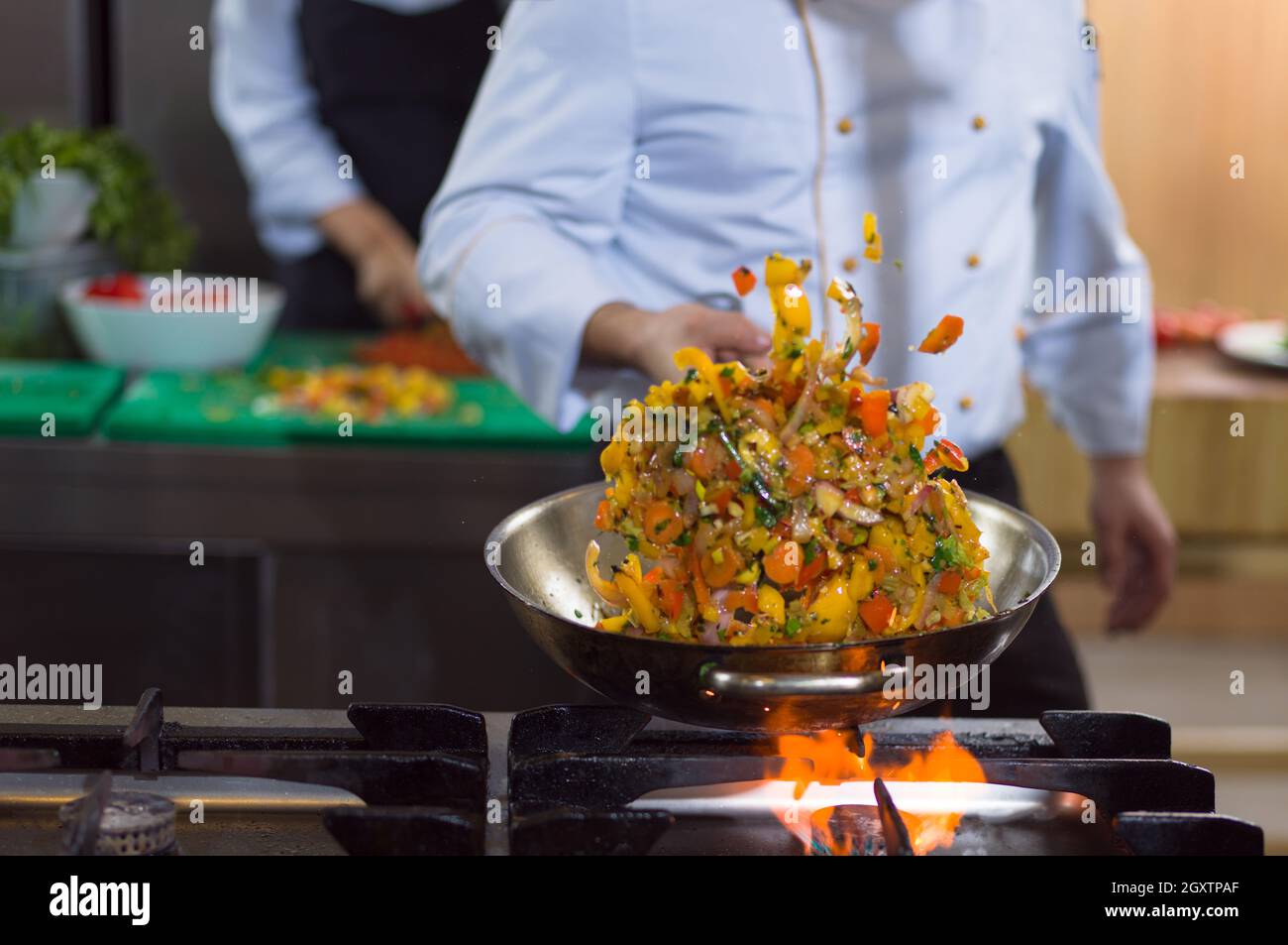 Young male chef flipping vegetables in wok at commercial kitchen Stock ...