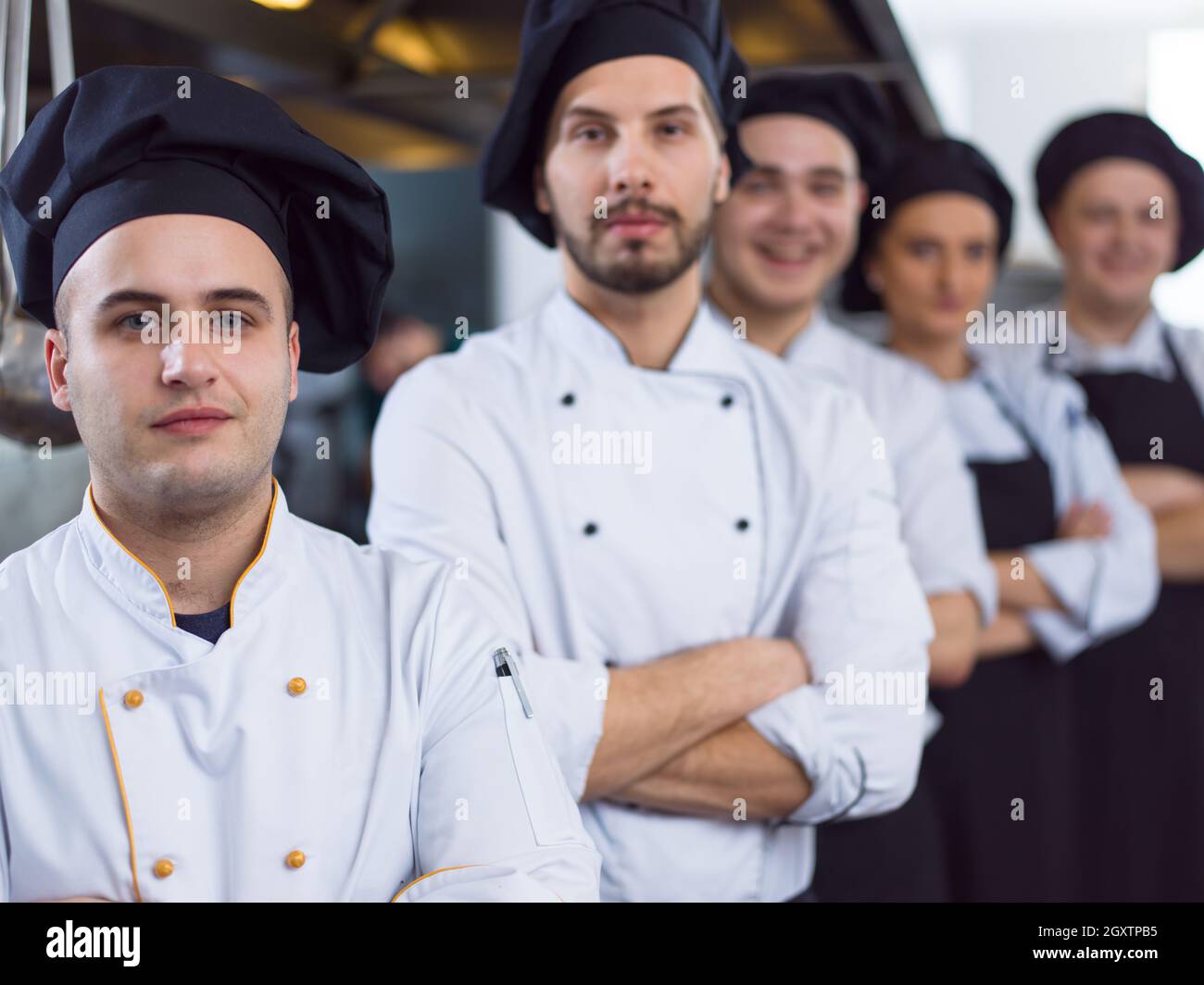 Portrait of group chefs standing together in commercial kitchen at ...