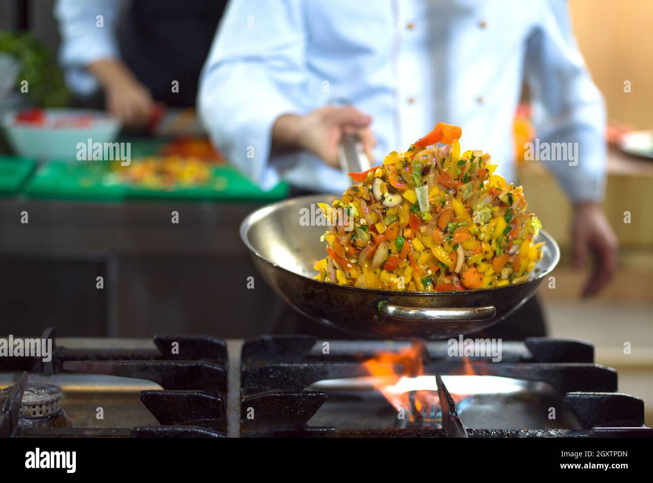 Young male chef flipping vegetables in wok at commercial kitchen Stock ...
