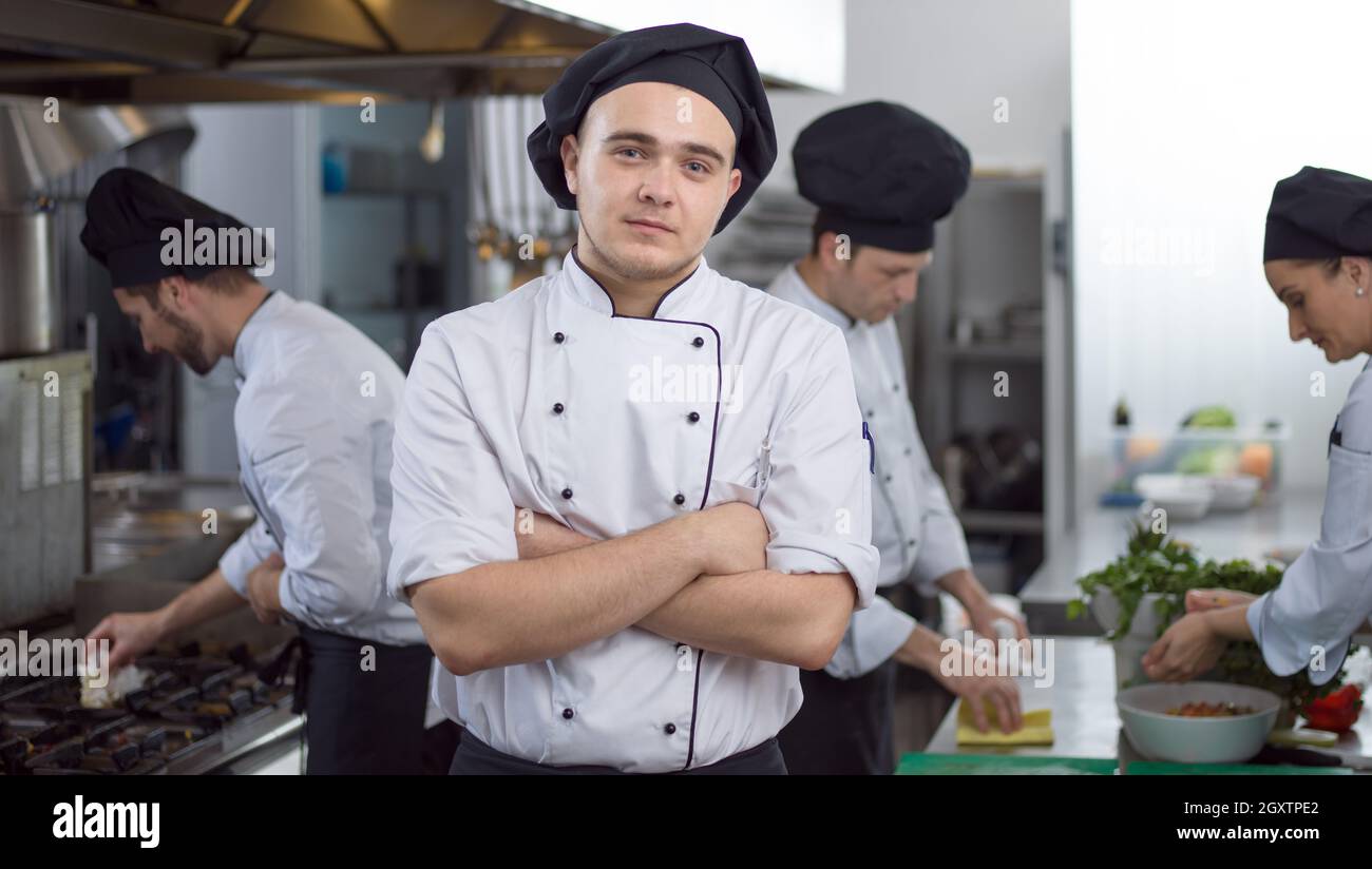 Portrait of young chef standing in commercial kitchen at restaurant ...