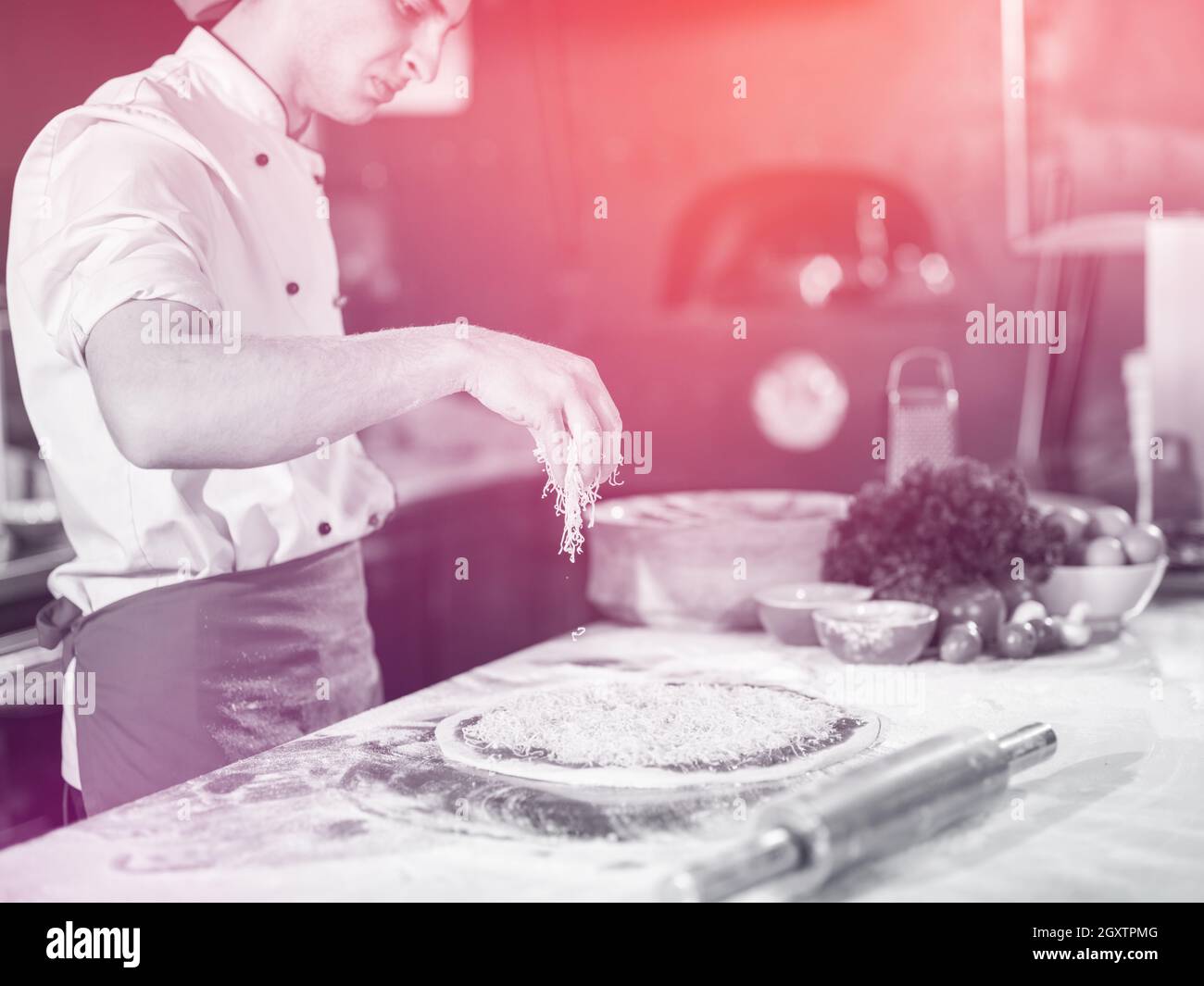 chef sprinkling cheese over fresh pizza dough on kitchen table Stock ...