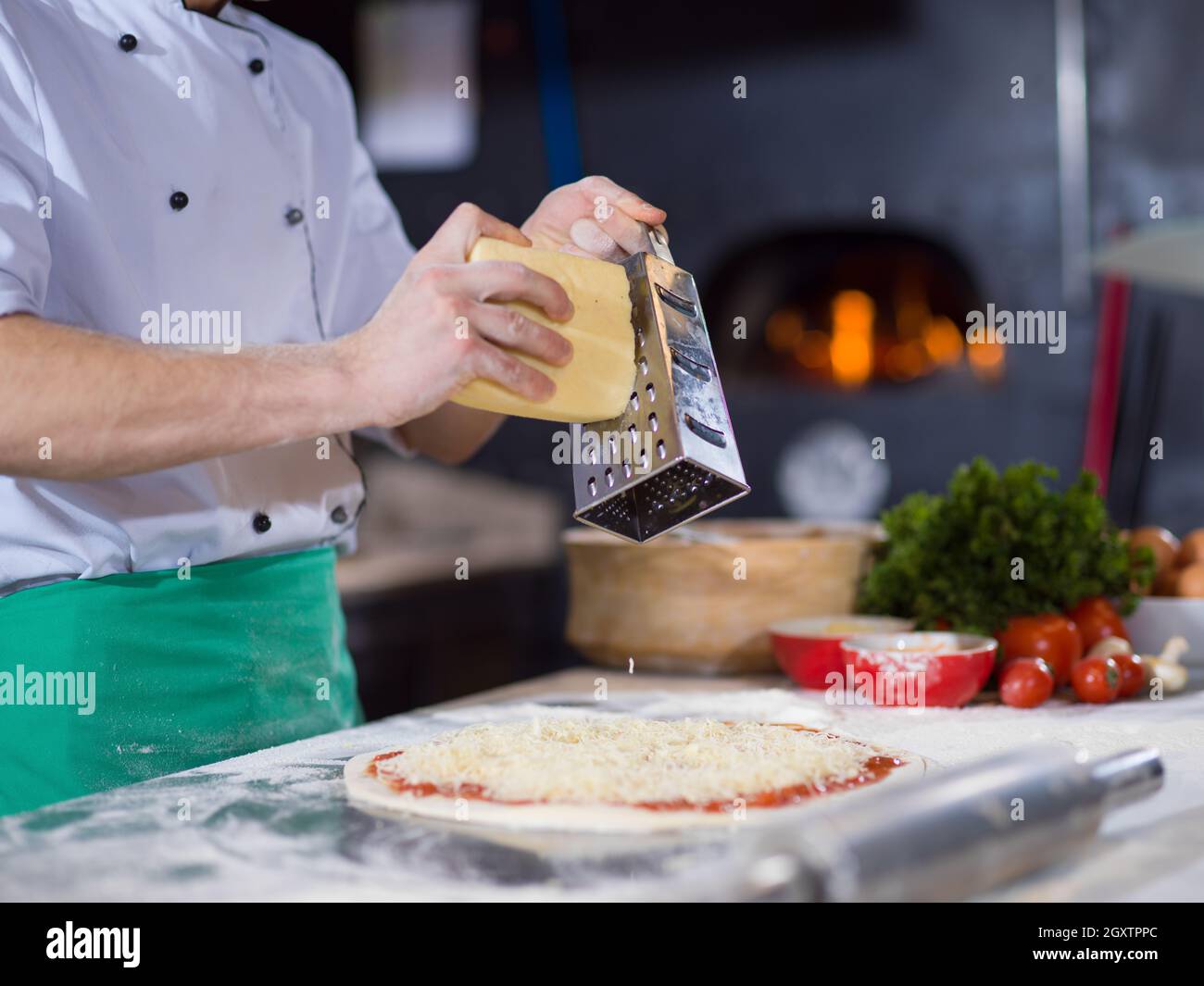 chef sprinkling cheese over fresh pizza dough on kitchen table Stock ...