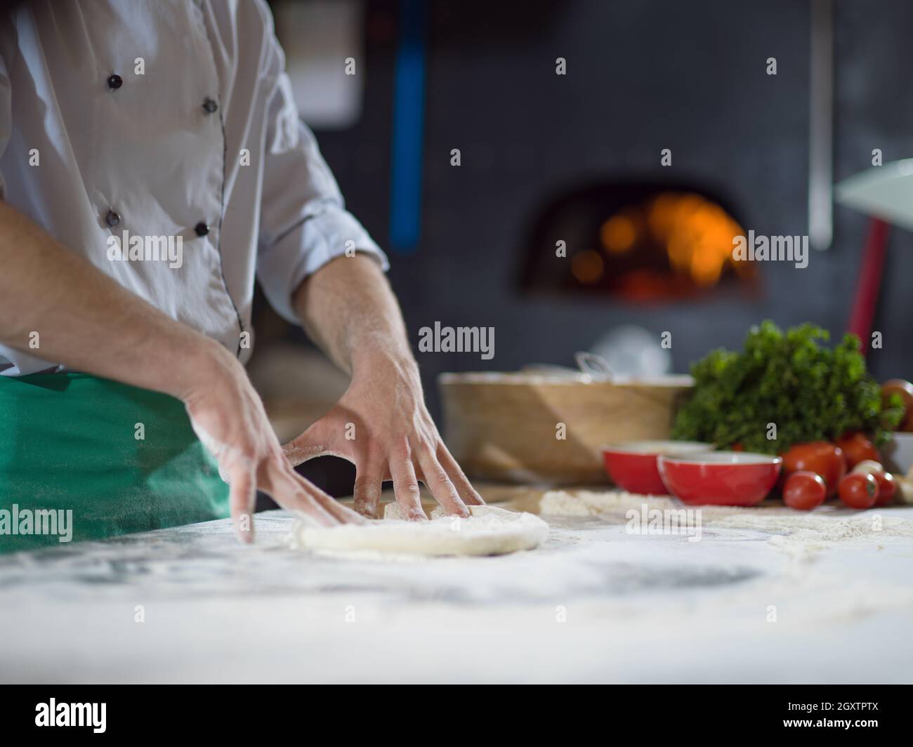 chef preparing dough for pizza rolling with hands on sprinkled with ...